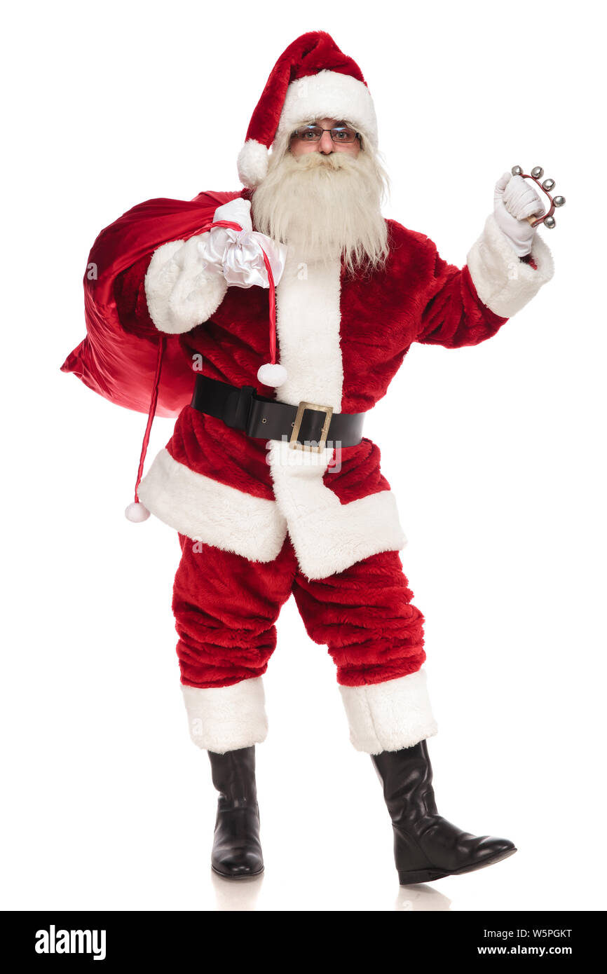 merry saint nick holds his red sack while ringing bell and standing on ...