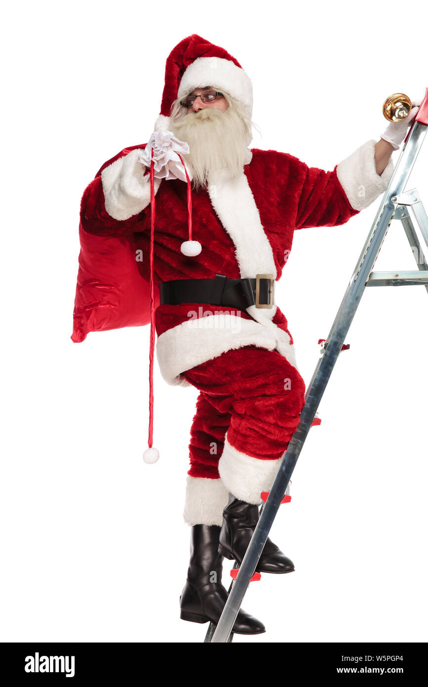 side view of santa claus standing on ladder and looking behind on white ...