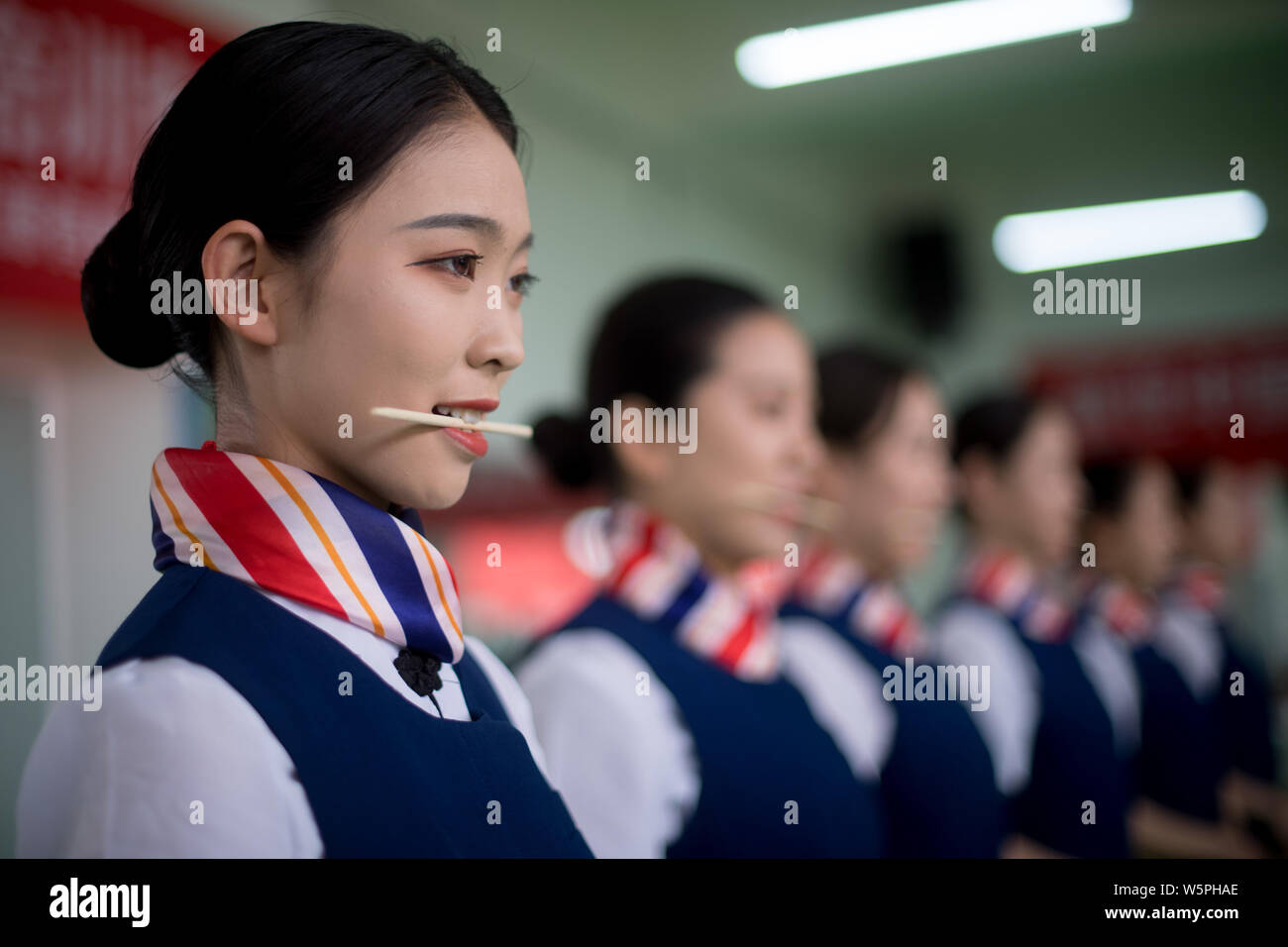 A Chinese volunteer practises smiling by biting chopsticks while ...