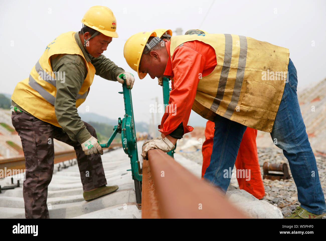 Chinese construction workers lay rails on crossties or railroad ...