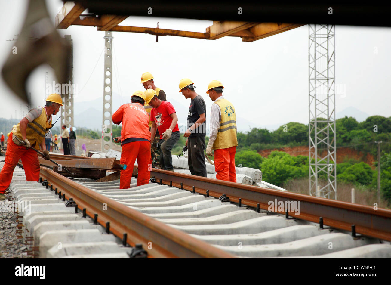 Chinese construction workers lay rails on crossties or railroad ...