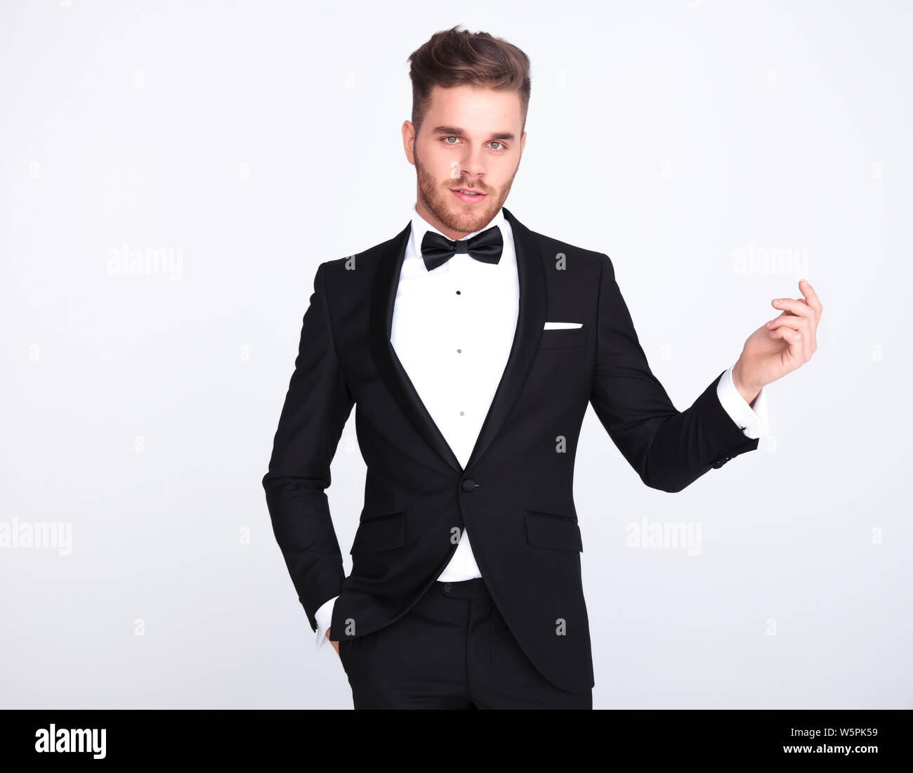 portrait of relaxed gentleman in tuxedo snapping fingers while standing ...