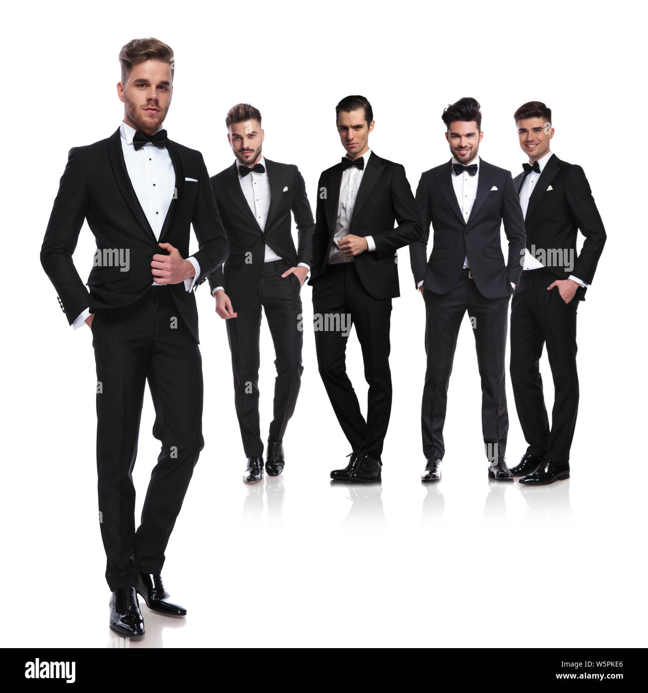 team of five groomsmen in tuxedoes standing on white background with ... team of five groomsmen in tuxedoes standing on white background with ...