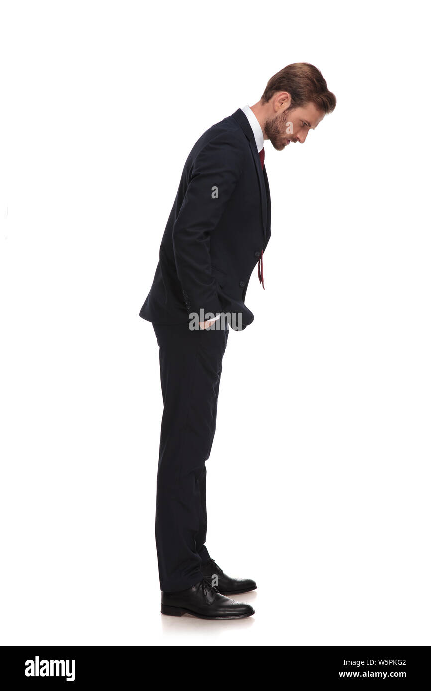side view of relaxed businessman looking down while standing on white ...