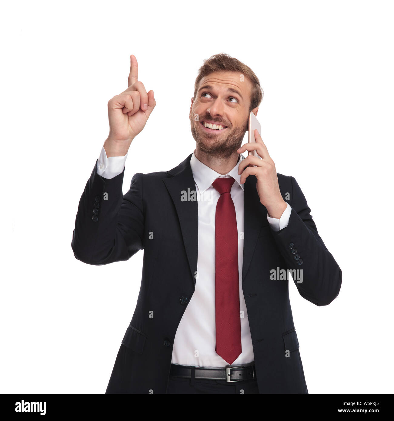 happy businessman on phone points finger and looks up while standing on ...