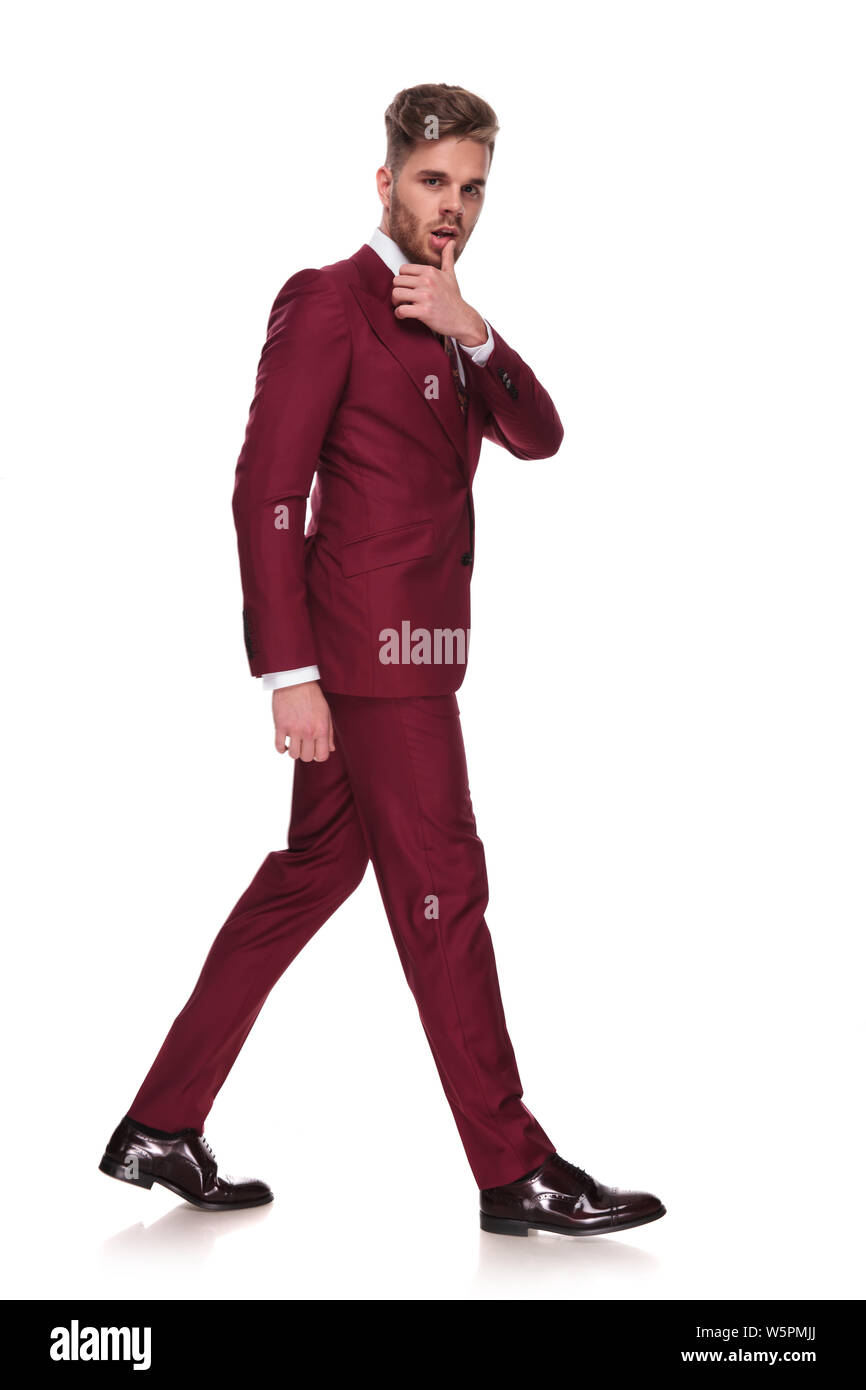 side view of sensual stylish man touching his lip while walking on ...