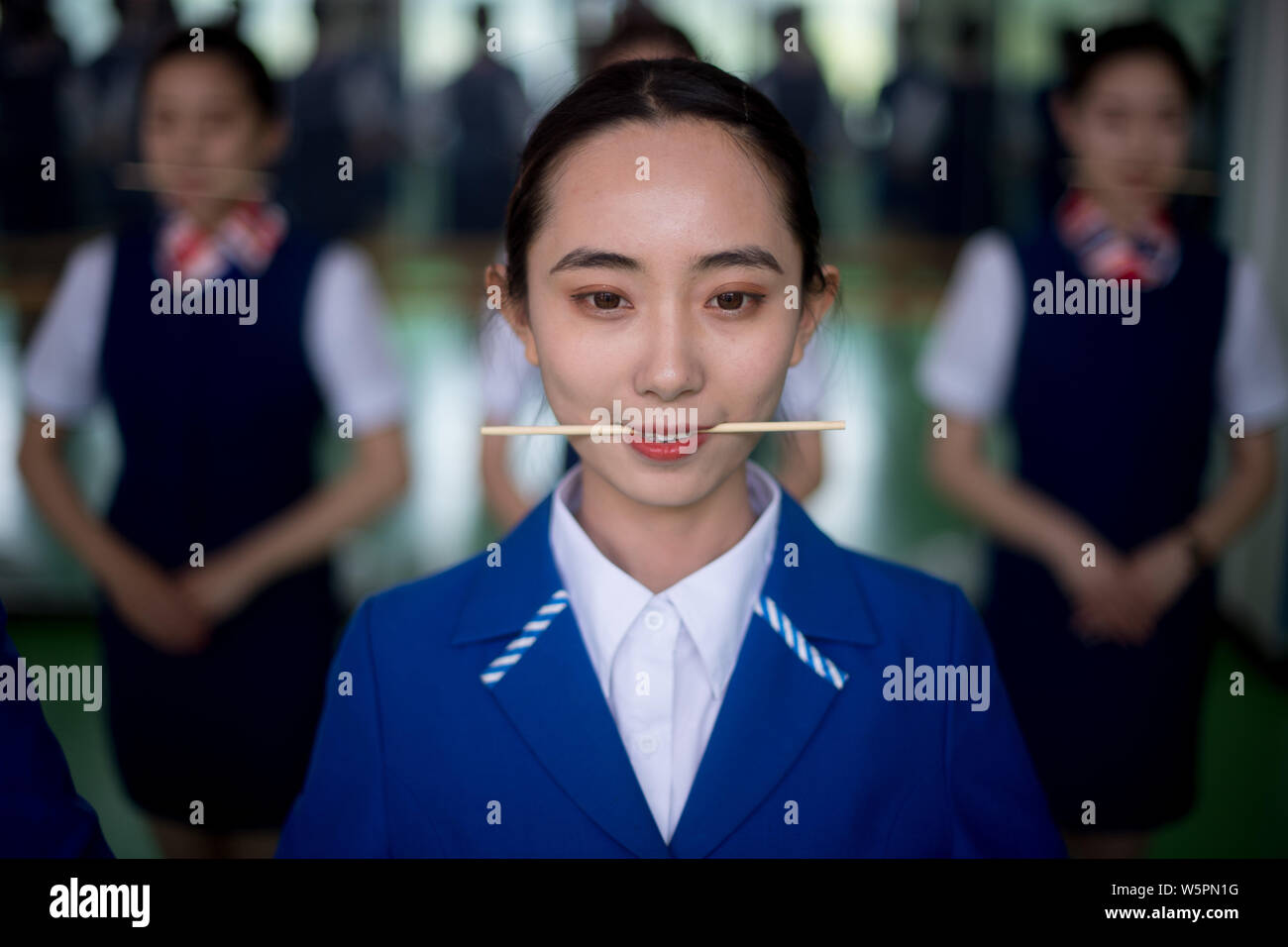 A Chinese volunteer practises smiling by biting chopsticks while ...