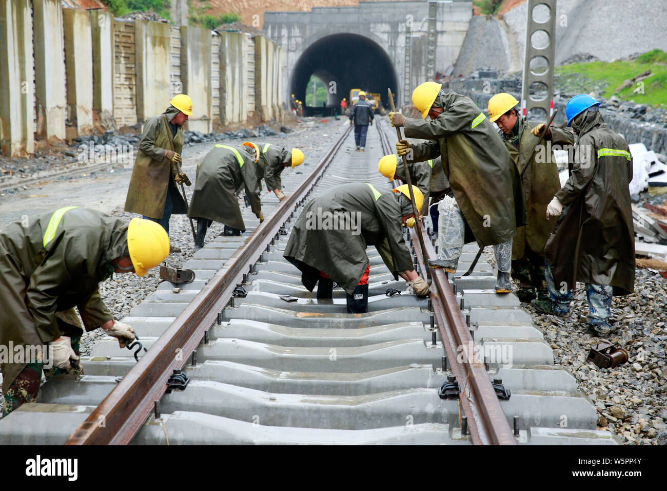 Chinese construction workers lay rails on crossties or railroad ...
