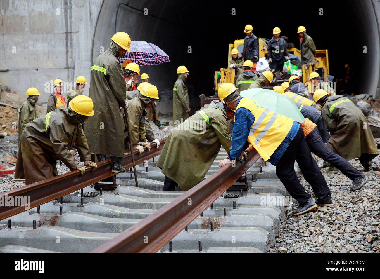 Chinese construction workers lay rails on crossties or railroad ...