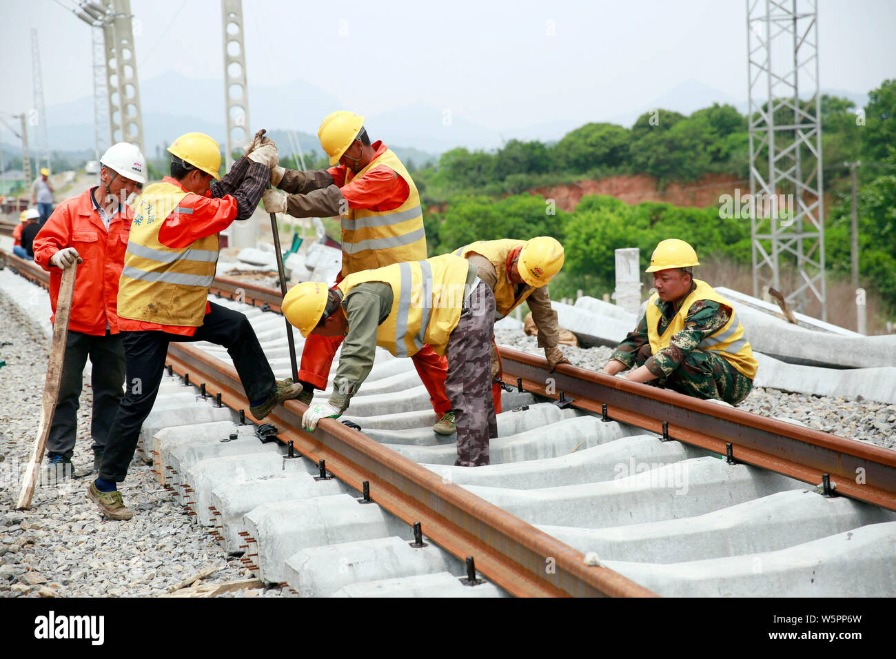 Chinese construction workers lay rails on crossties or railroad ...