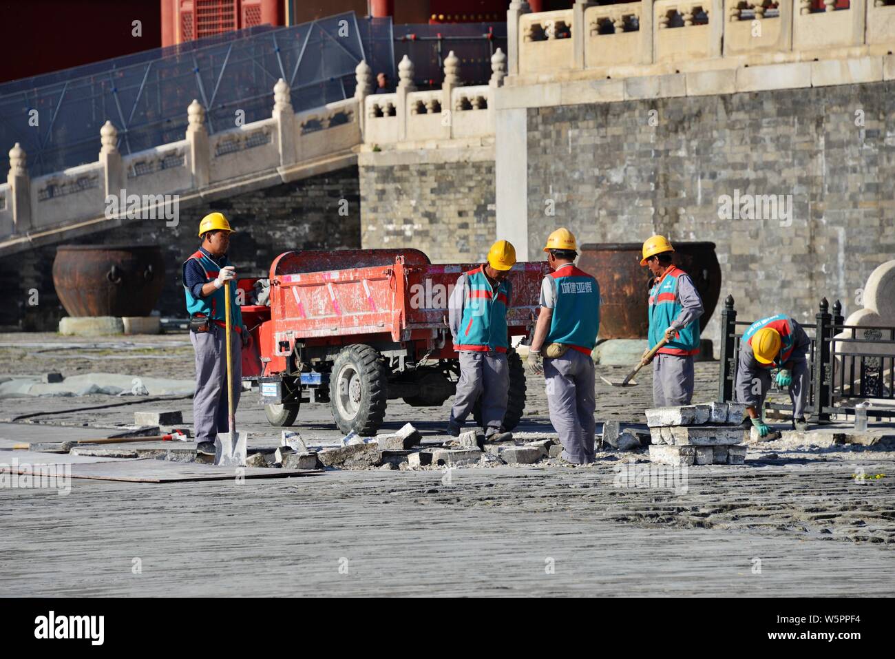 Chinese construction workers renovate the ground of the square in front ...