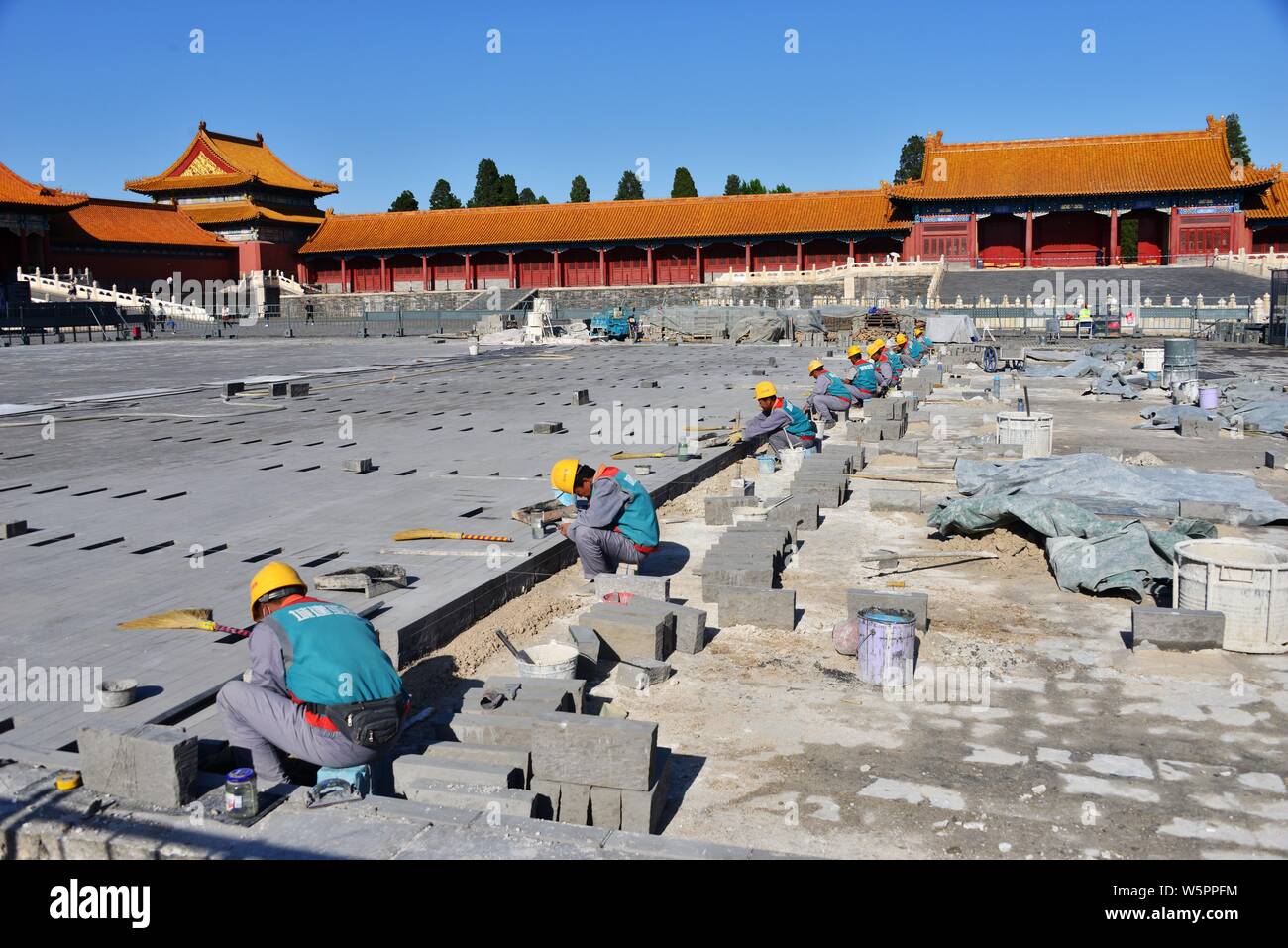 Chinese construction workers renovate the ground of the square in front ...