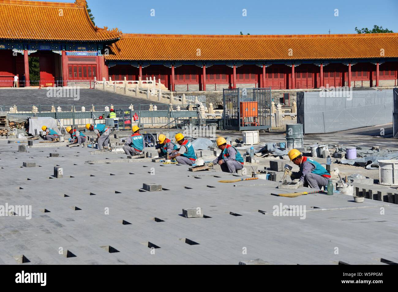 Chinese construction workers renovate the ground of the square in front ...