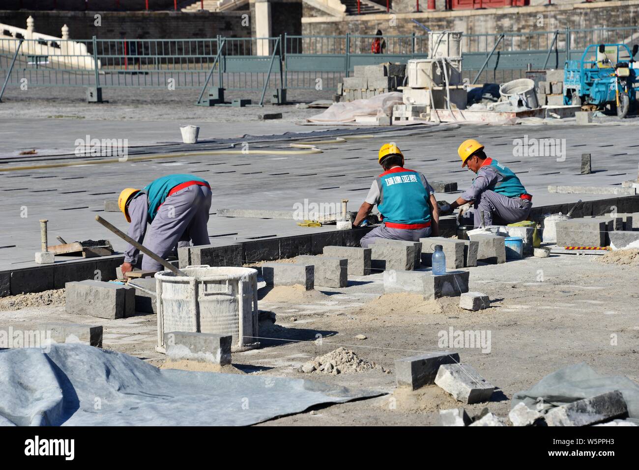 Chinese construction workers renovate the ground of the square in front ...