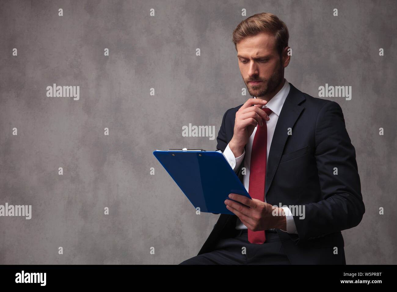 confused young businessman is reading data on a clipboard and thinks ...