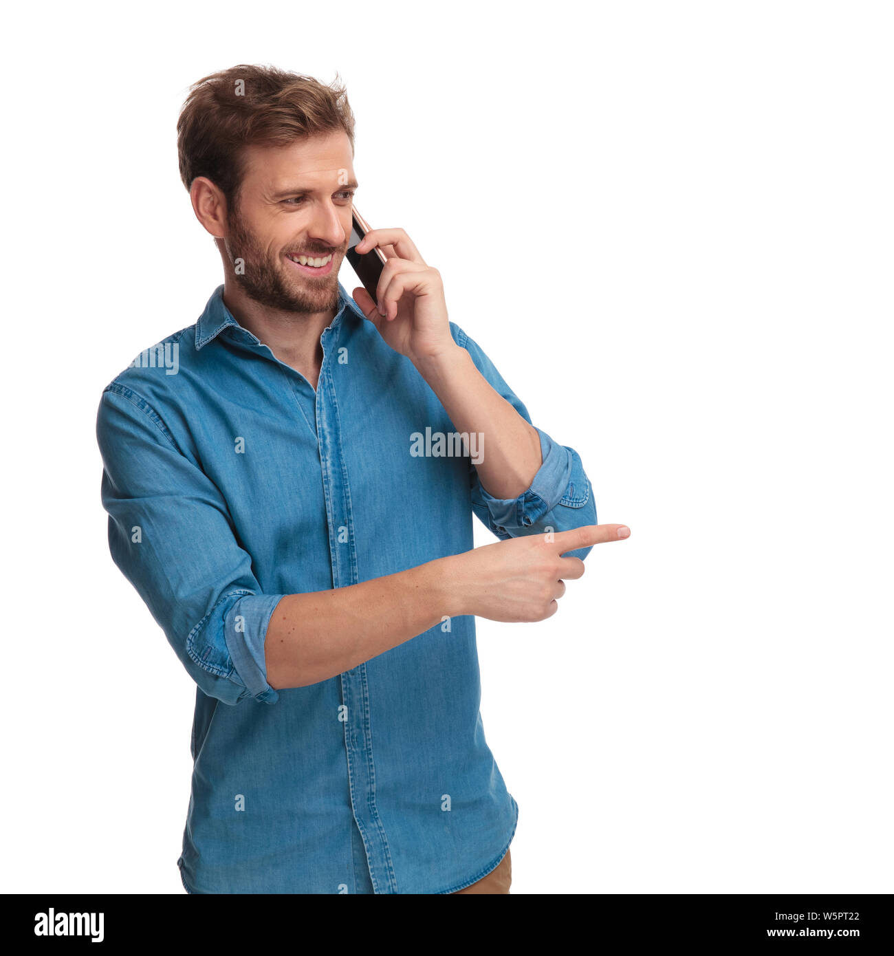 smiling casual man talking on the phone points finger to side at ...