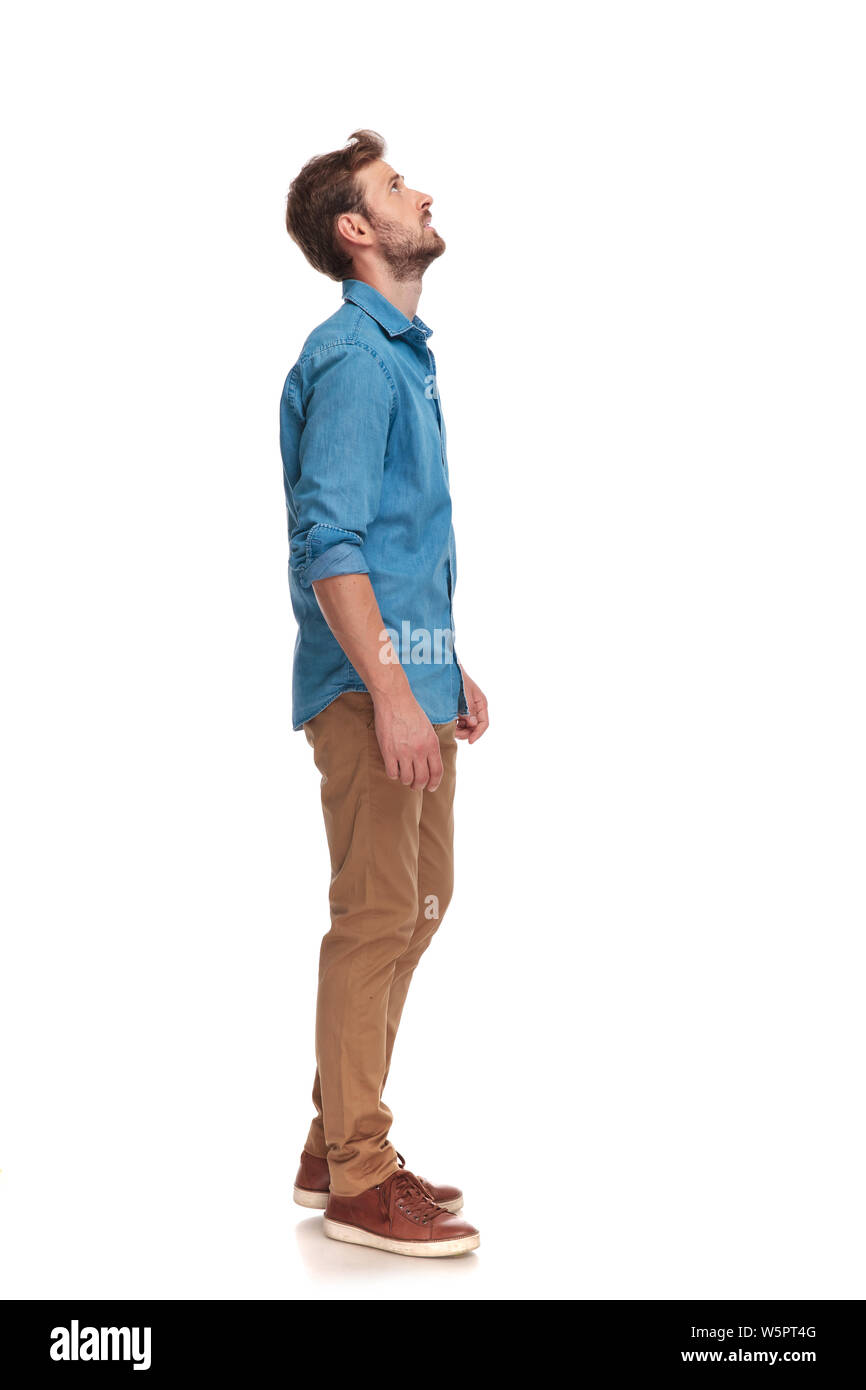side view of a casual man looking up at something on white background ...
