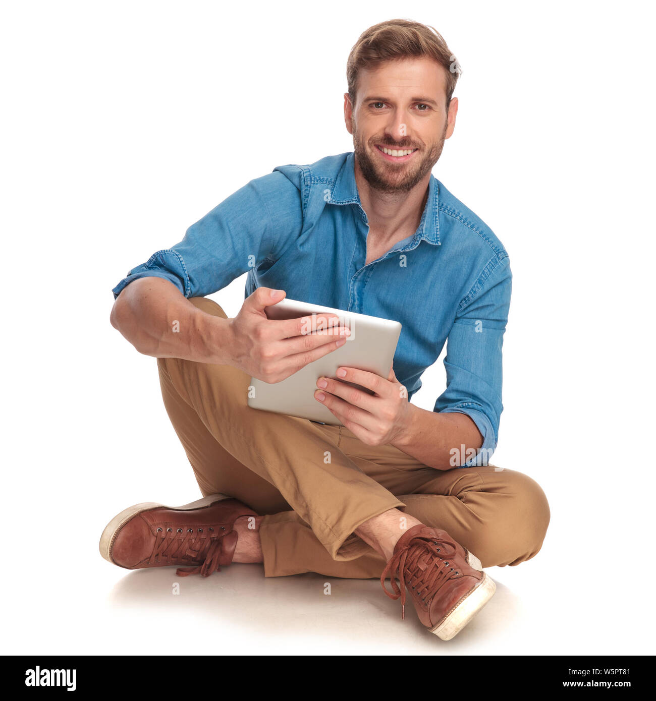 happy casual man sitting and holding tablet is smiling on white ...