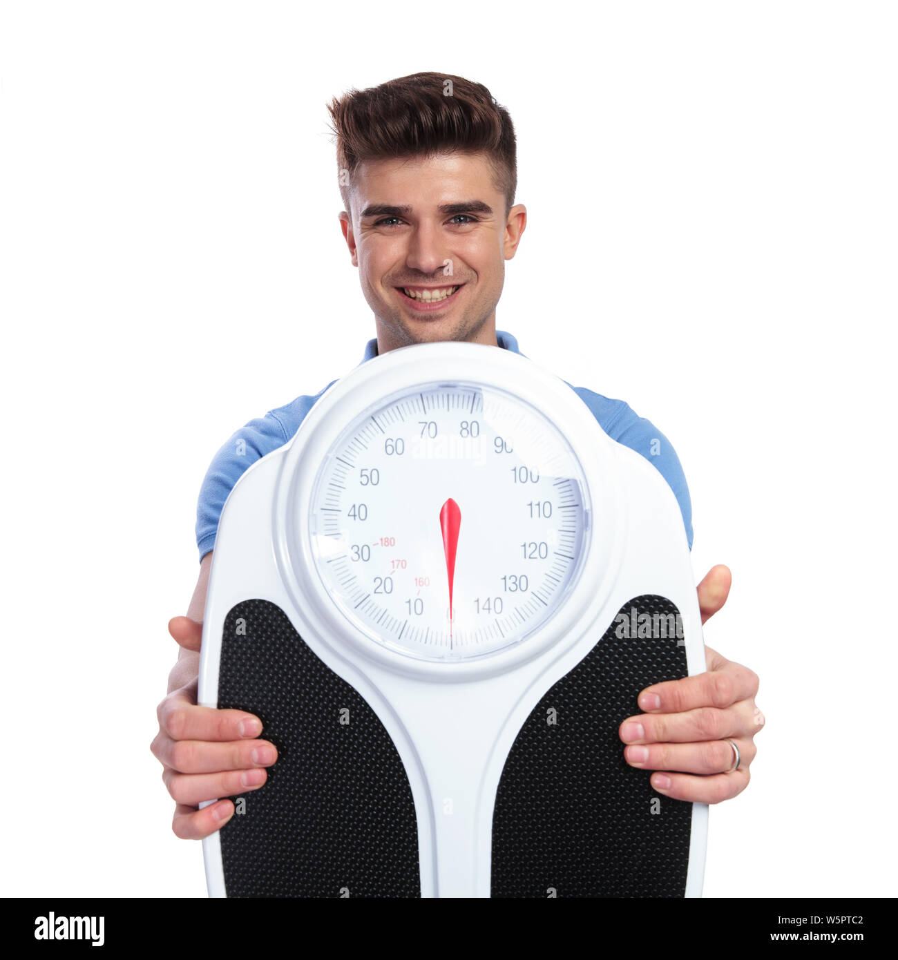 smiling casual man holding and showing a scale on white background ...