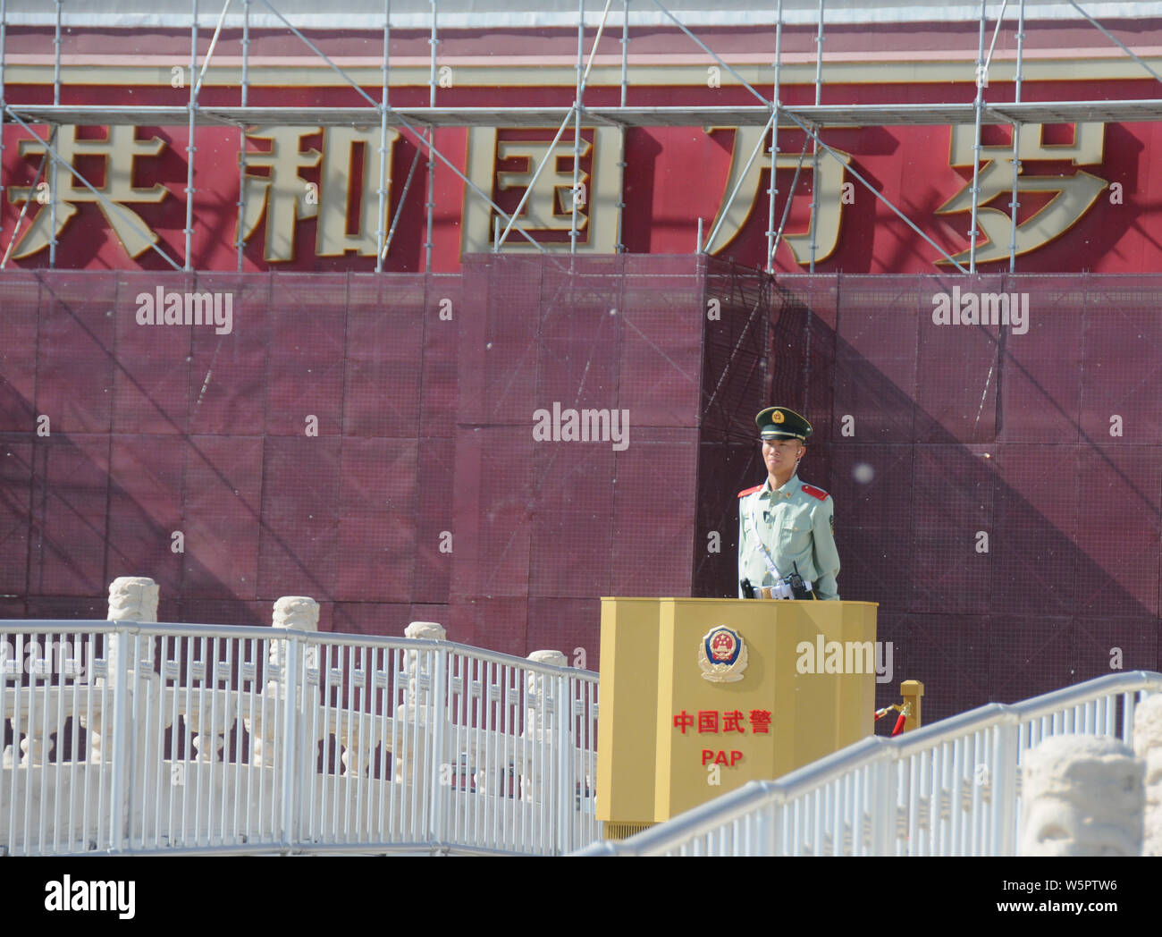A Chinese paramilitary policeman stands guard in front of scaffoldings ...