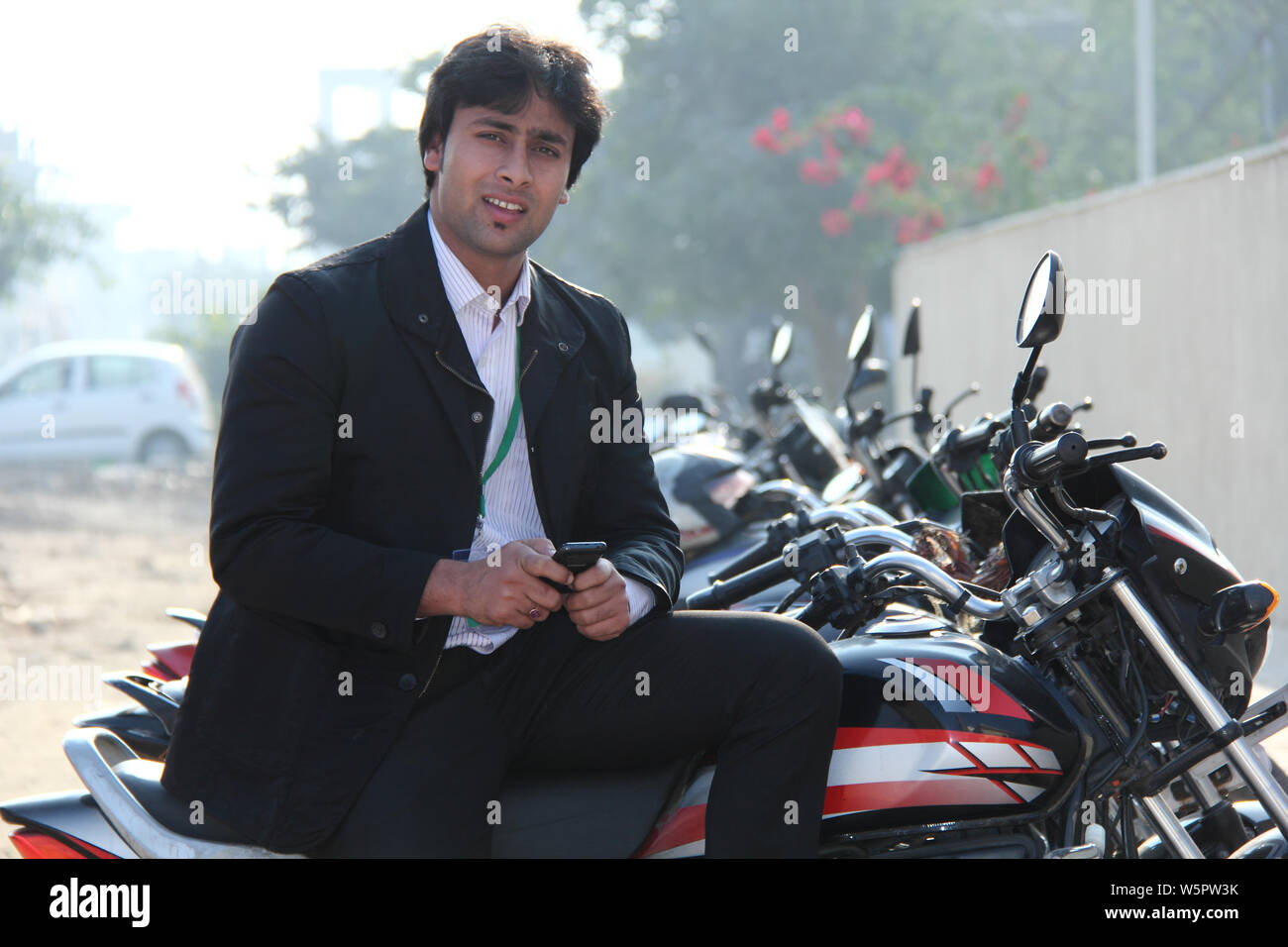 Salesman sitting on a motorcycle and using mobile phone Stock Photo - Alamy
