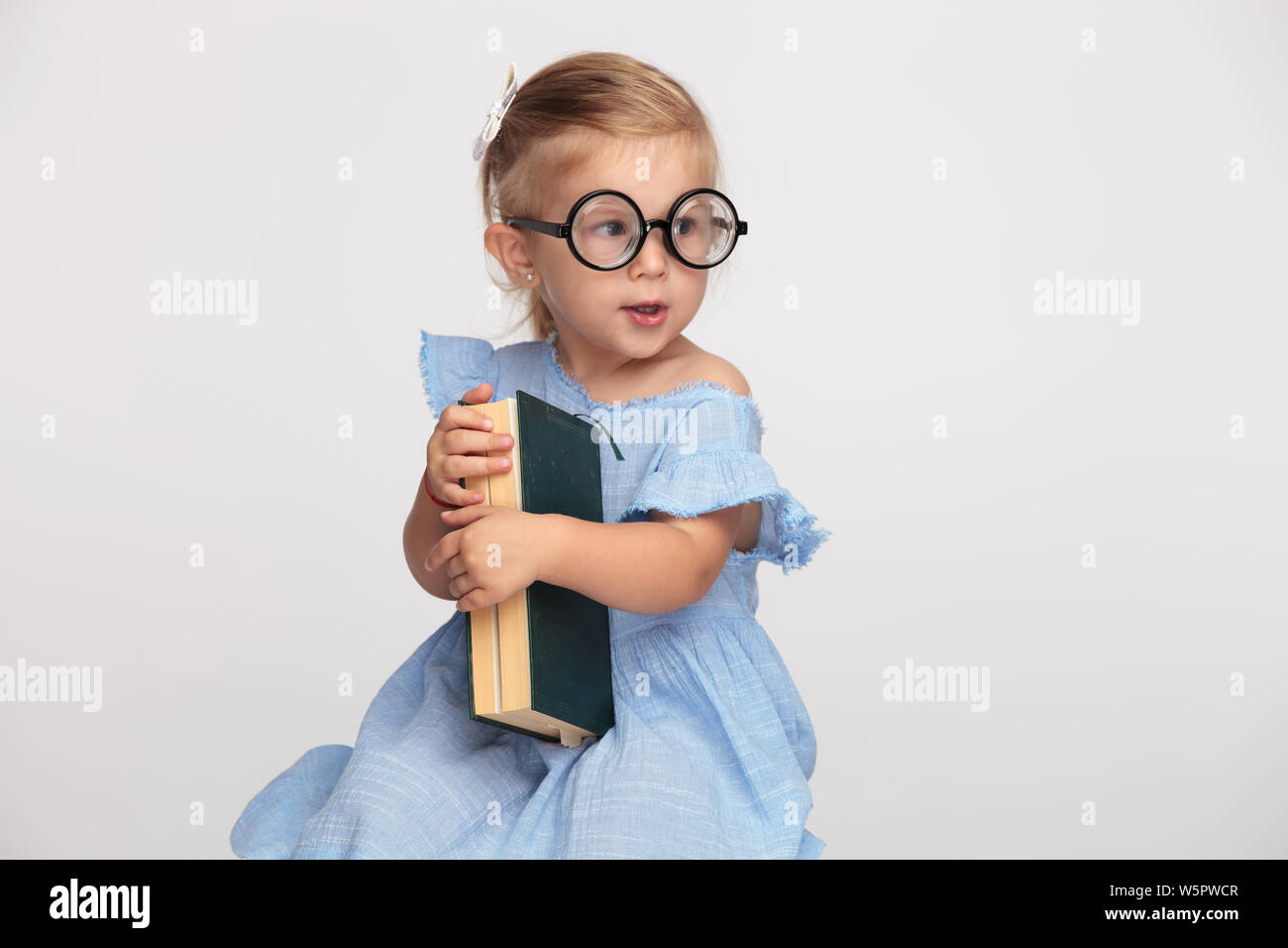 cool nerdy little girl holding her book and waits for the school to ...