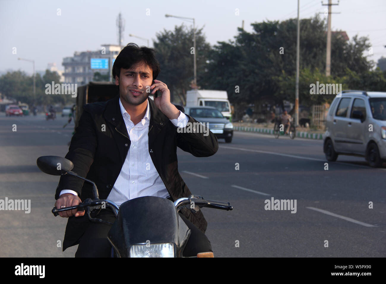 Man talking on mobile phone while riding a motorcycle without helmet ...
