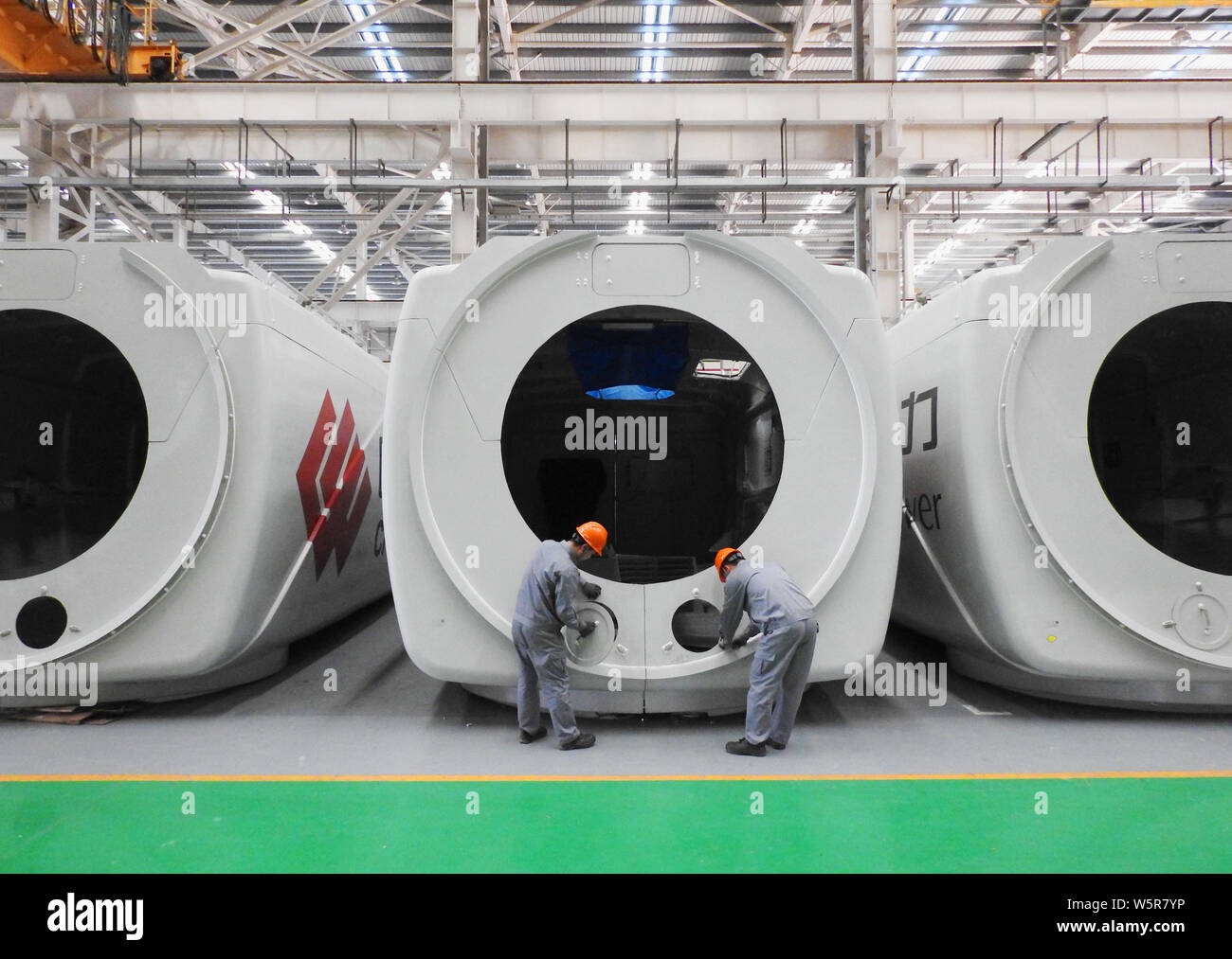 Chinese workers assemble wind turbine hubs on the assembly line in ...