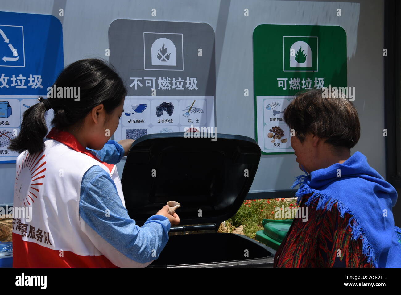 A Chinese volunteer introduces garbage sorting to a villager in Dongchu ...