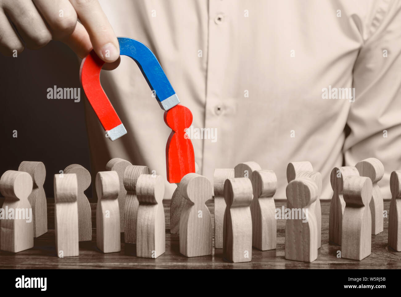 businessman pulls out a red figure of a man from the crowd with the ...