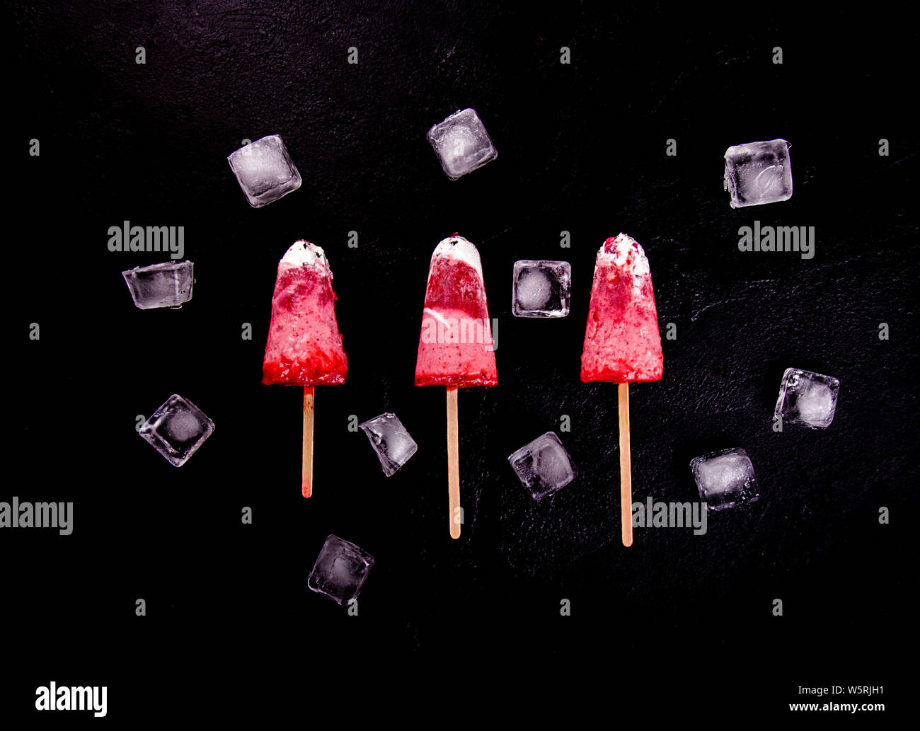 Strawberry ice cream popsicle lolly pops with whipped cream on black ...
