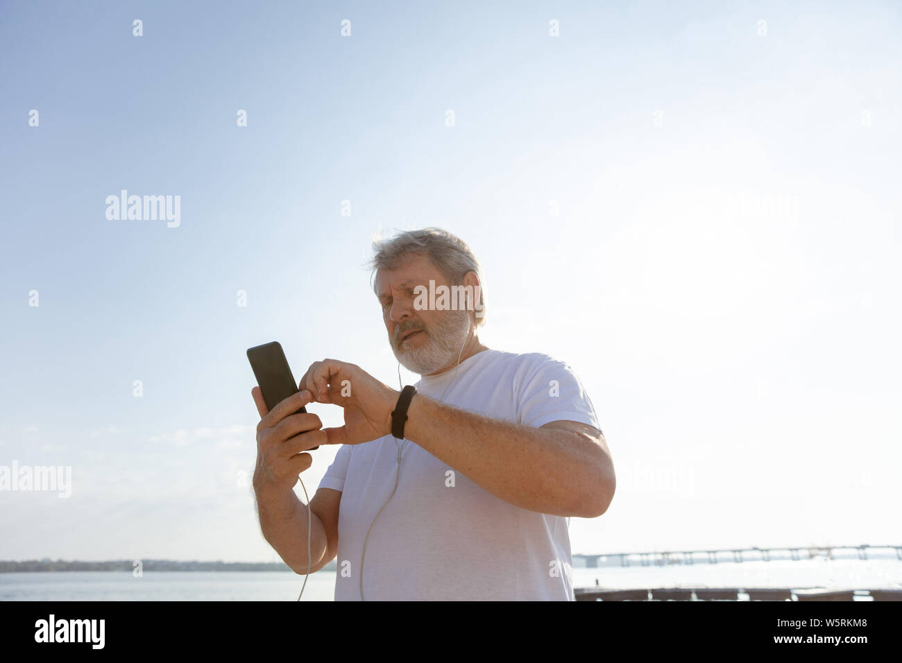 Senior man as runner with fitness tracker at the riverside. Caucasian ...