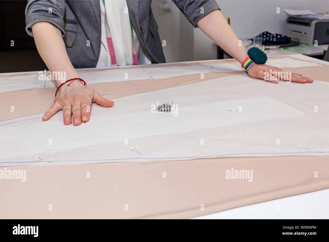 Female tailor hands with cloth, pattern and needle in the workshop ...