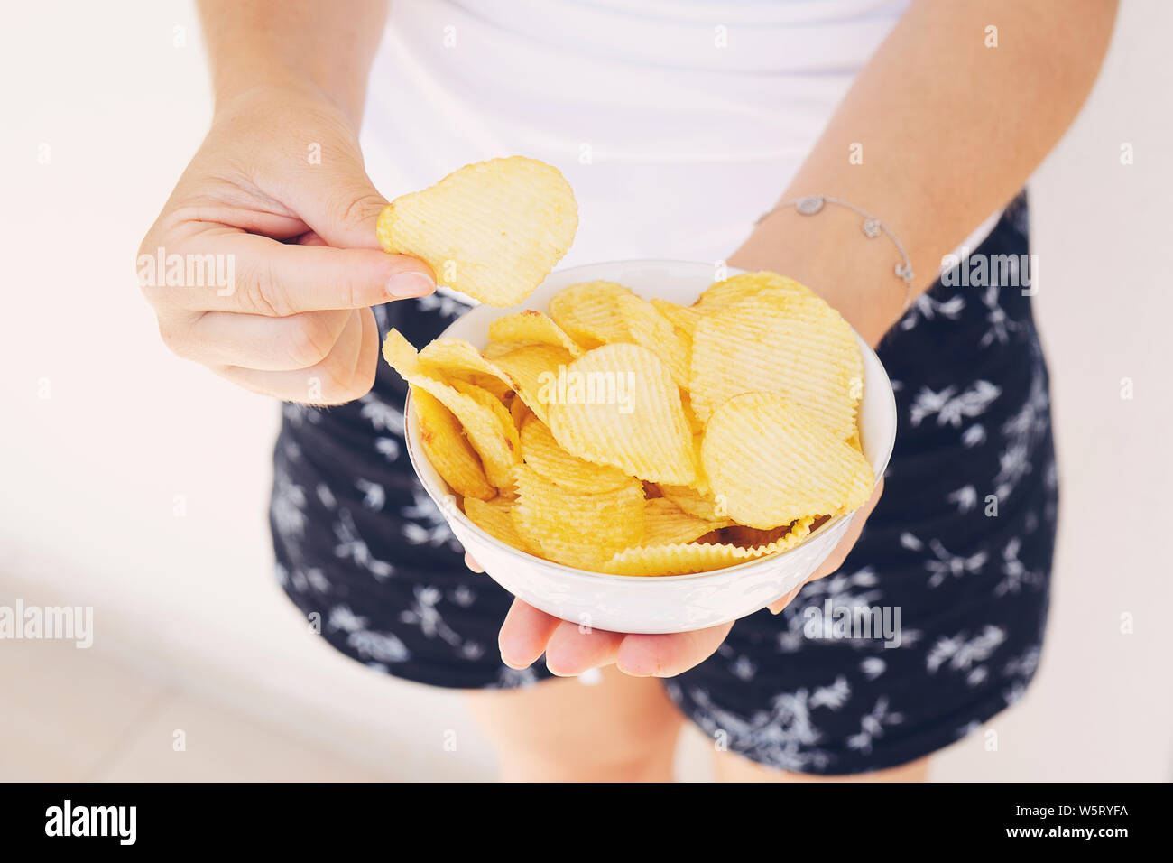 A girl holding the big potato chips bowl. Asking to eating together ...