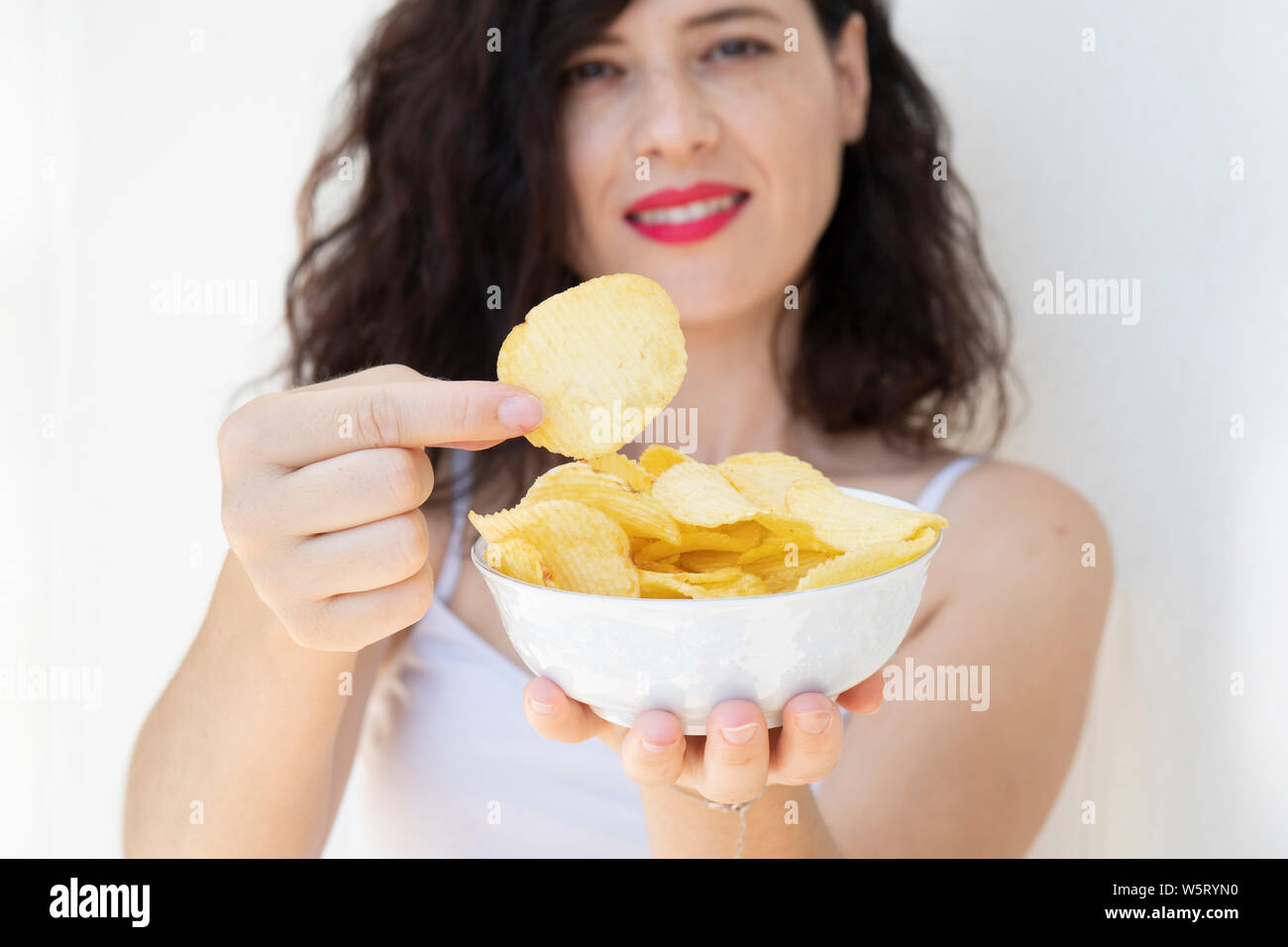 A girl holding the big potato chips bowl. Asking to eating together ...