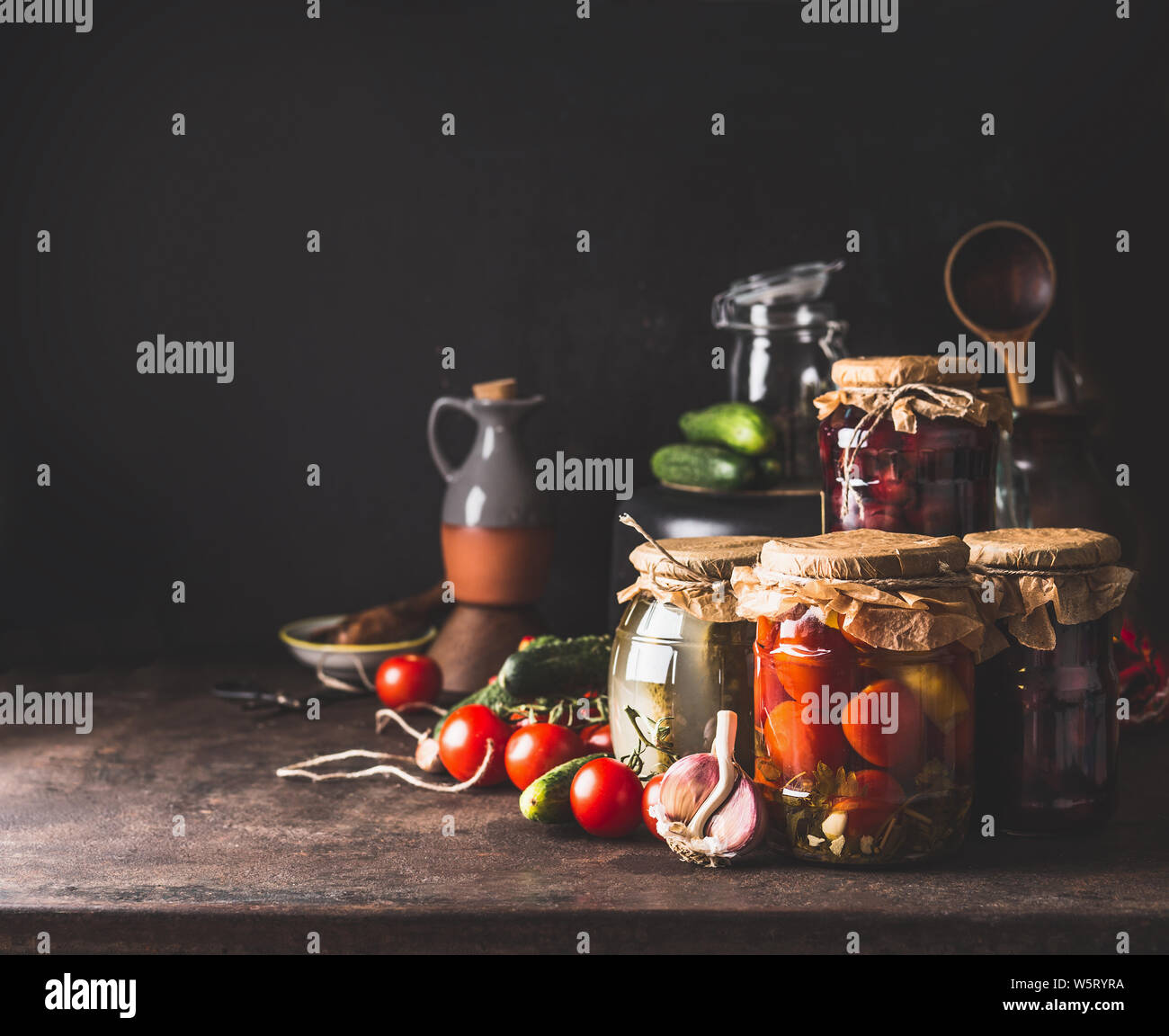 Vegetables and fruits canning. Various preserve glass jars on dark ...