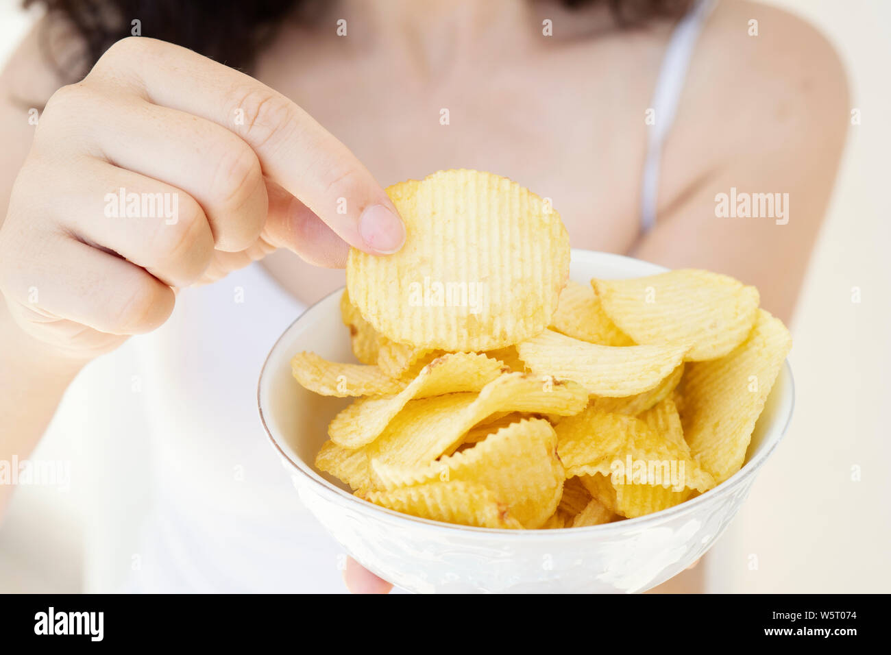 A girl holding the big potato chips bowl. Asking to eating together ...
