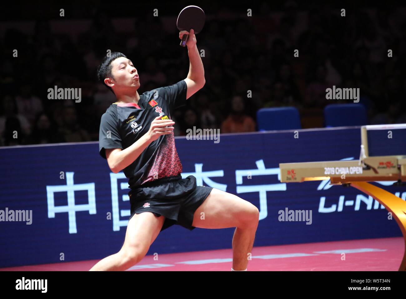 Xu Xin of China returns a shot to Lin Gaoyuan of China in the semifinal ...