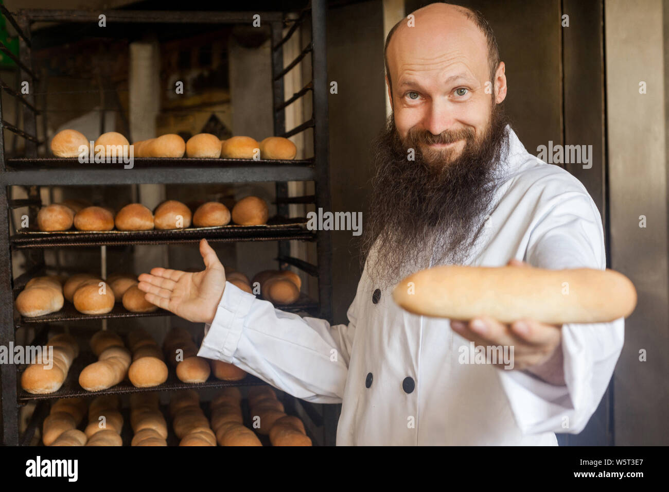 Please take it. Portrait of attractive positive young adult baker with ...