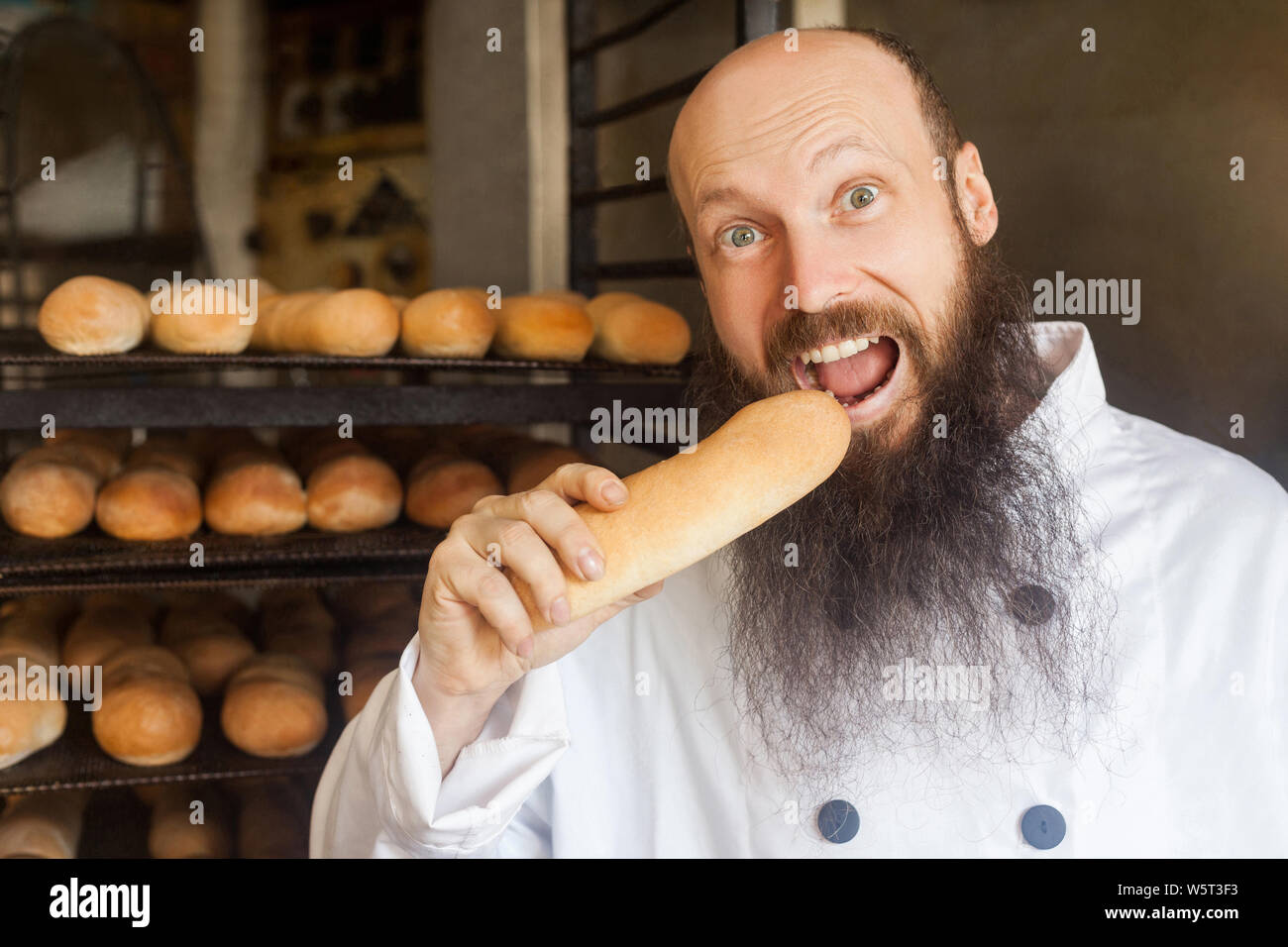 Portrait of happy young adult hungry baker with long beard in white ...