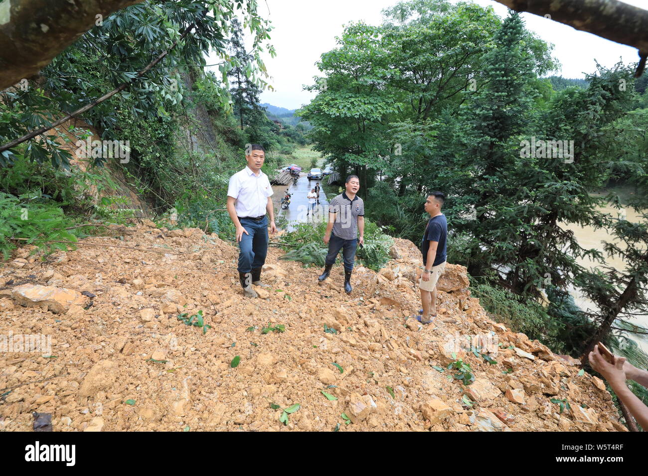 Chinese rescuers clear away mud and stones on a flooded road caused by ...