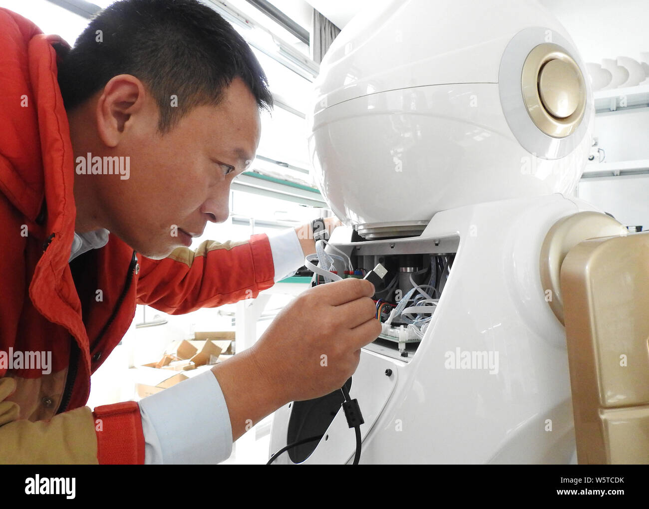 A Chinese worker debugs a batch of commercial service robots at the ...