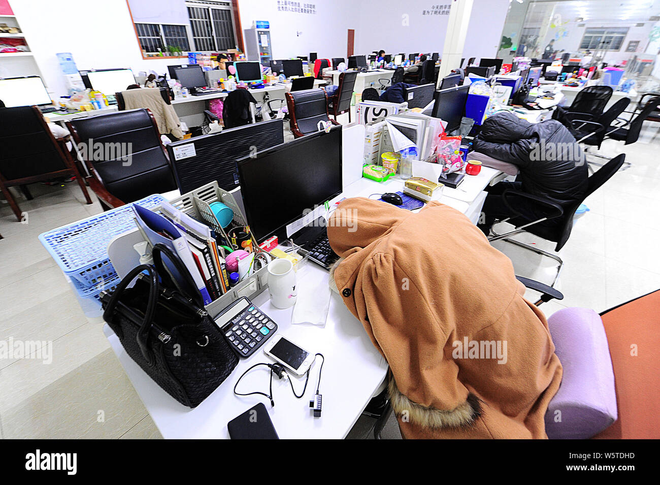 --FILE--Chinese employees take a nap as they work overtime at midnight ...