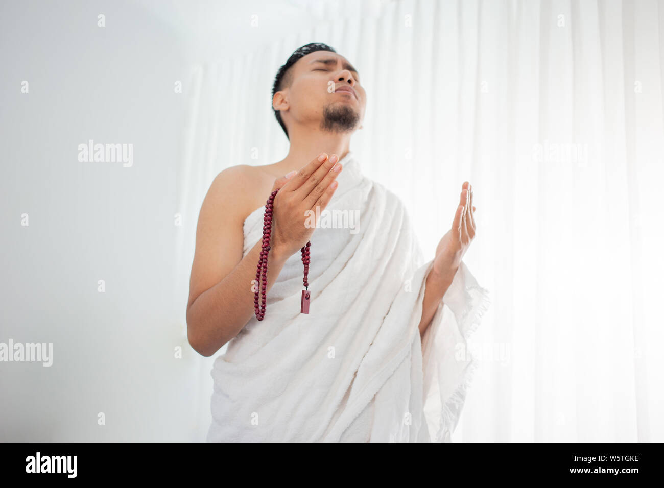 Muslim man praying in white traditional clothes Stock Photo - Alamy