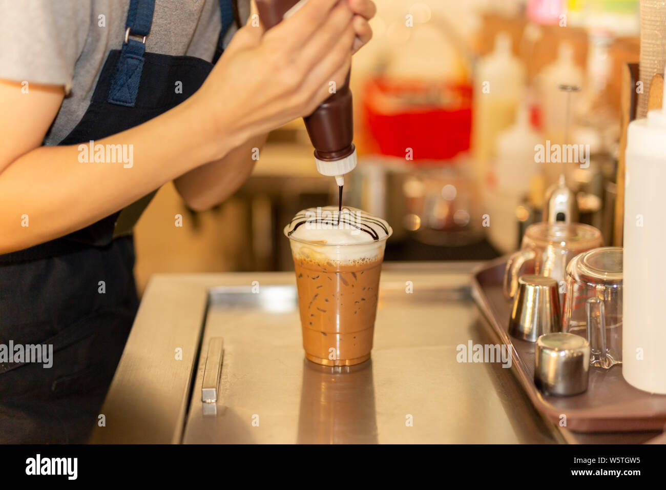 Barista squeezing chocolate cream on cream in iced chocolate drink ...