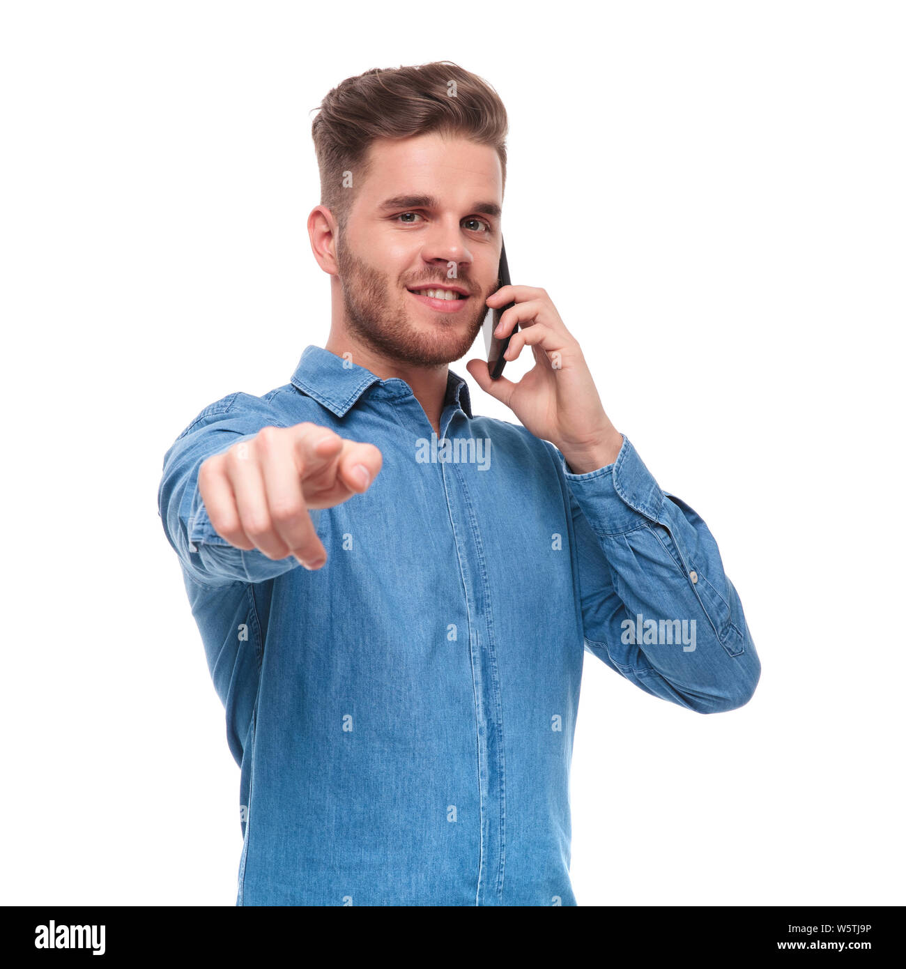 young casual man talking on the phone points finger while standing on ...