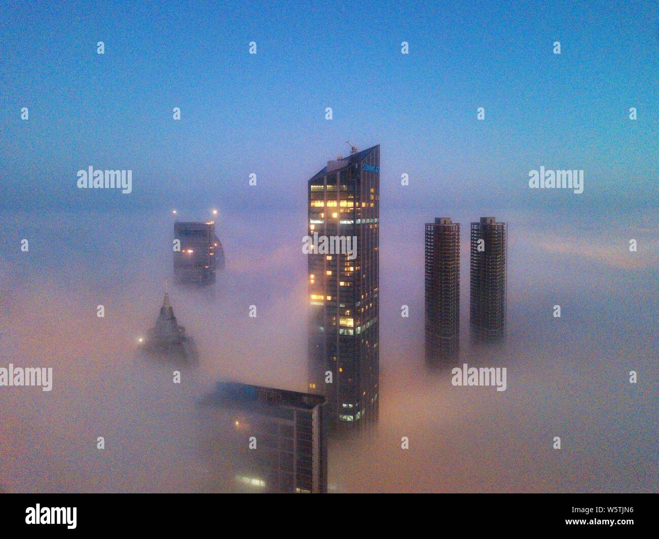 High-rising buildings and skyscrapers are shrouded by heavy fog in Wuxi ...