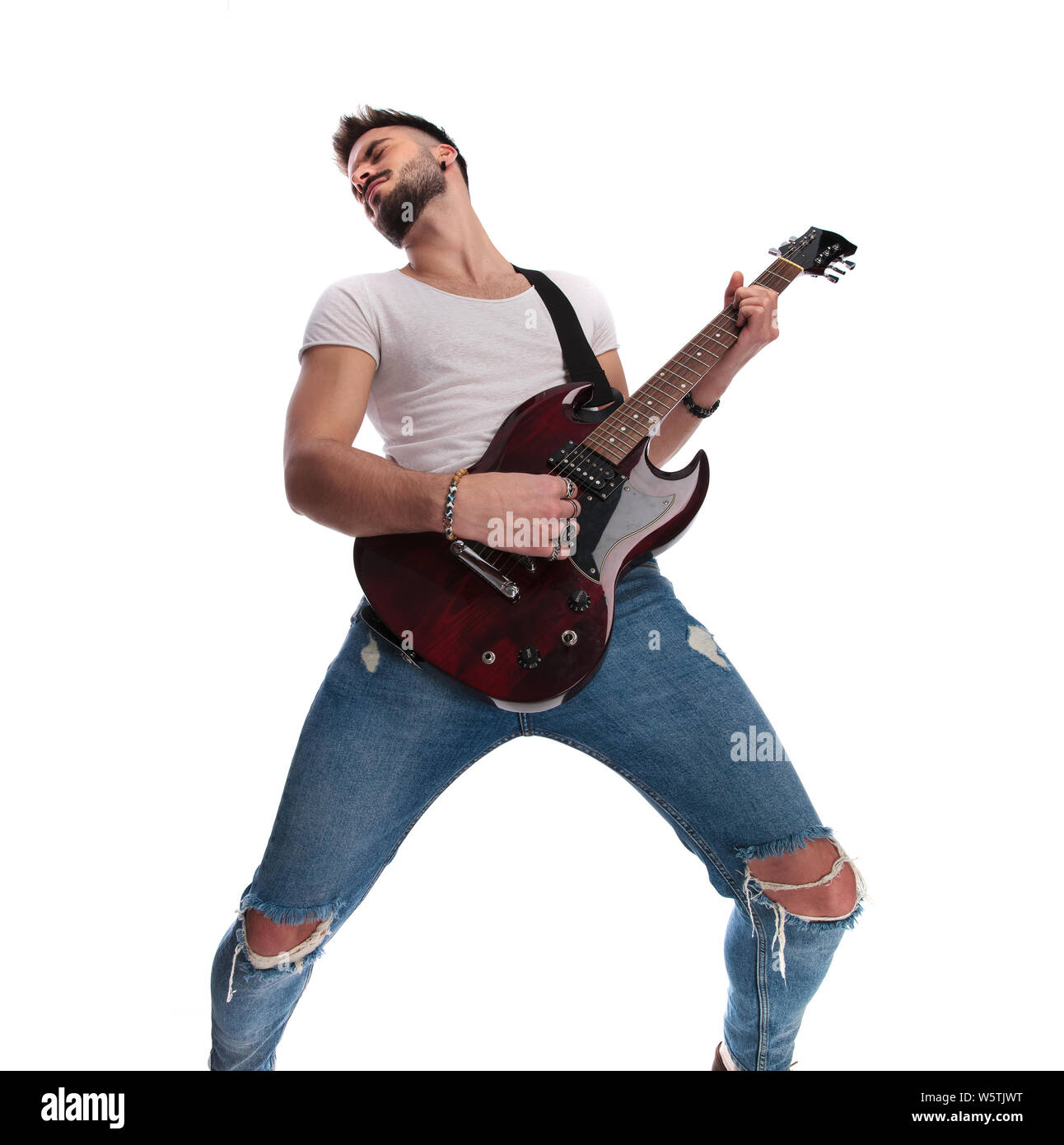 excited young guitarist playing the guitar and leaning back while ...