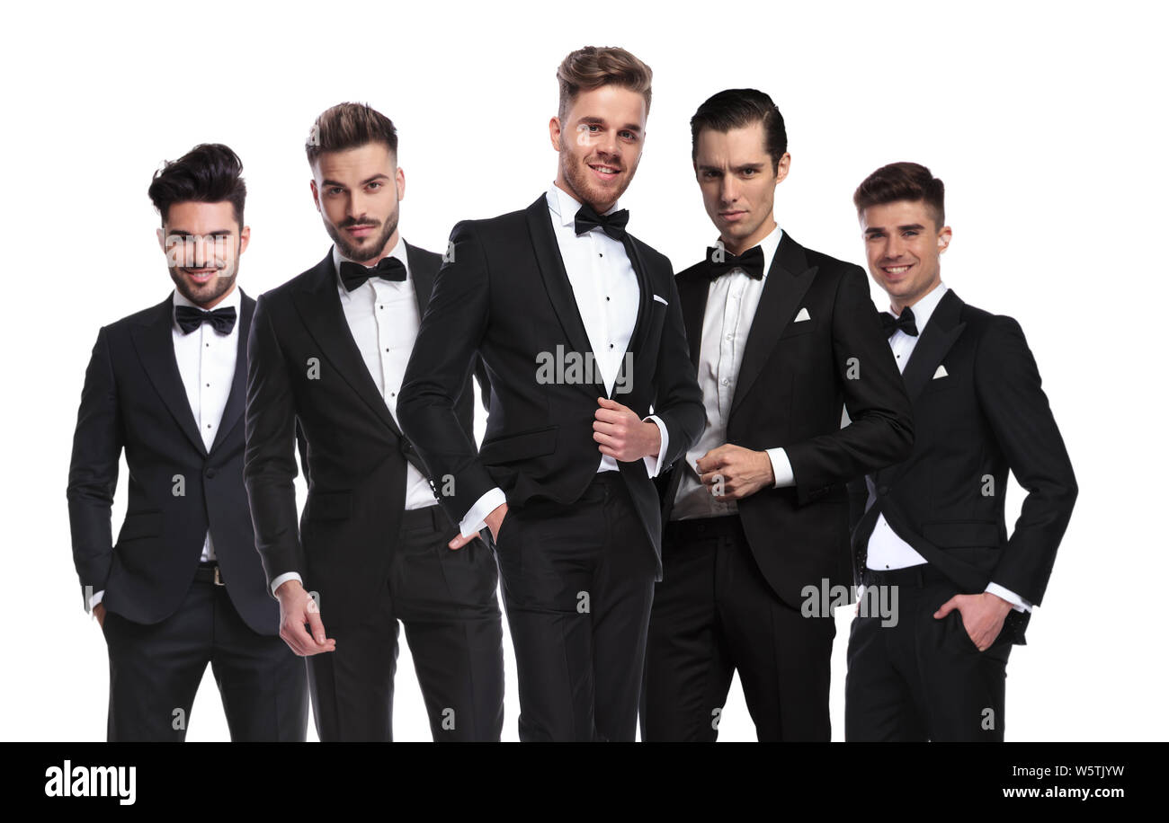 portrait of group of five elegant men in tuxedoes standing on white ...