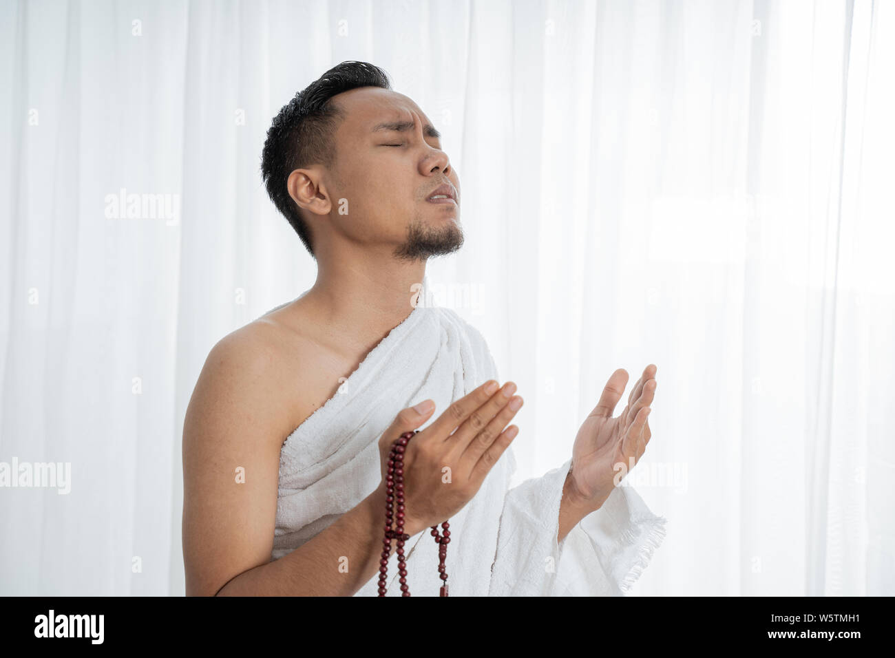Muslim man praying in white traditional clothes Stock Photo - Alamy